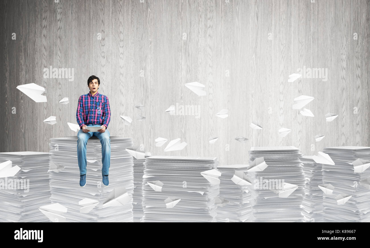 Attractive man sitting on pile of paper documents Stock Photo - Alamy