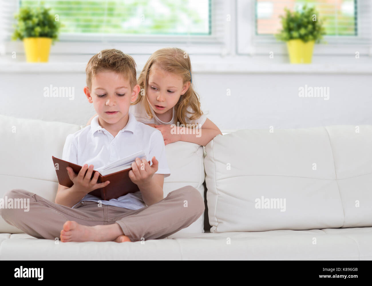 Little brother and sister reading book at home Stock Photo - Alamy