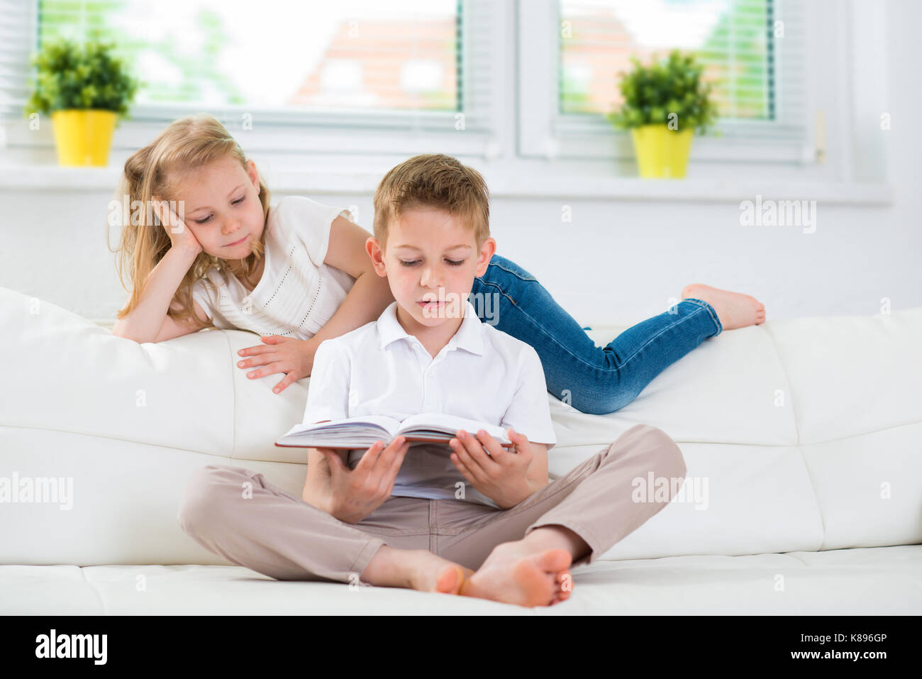 Little brother and sister reading book at home Stock Photo - Alamy