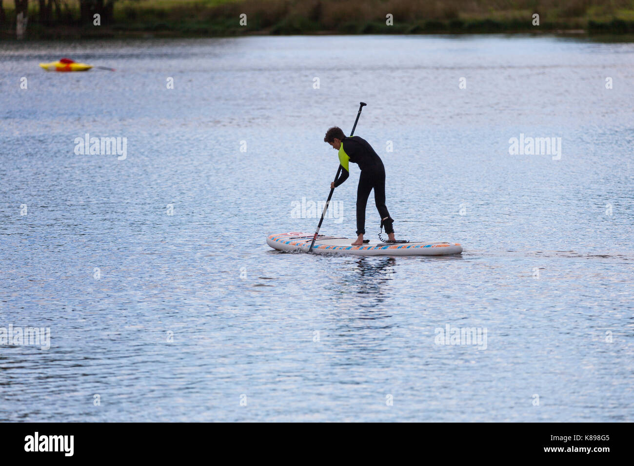 Youth paddle boarding on the Conningbrook lakes, Ashford, Kent, UK ...