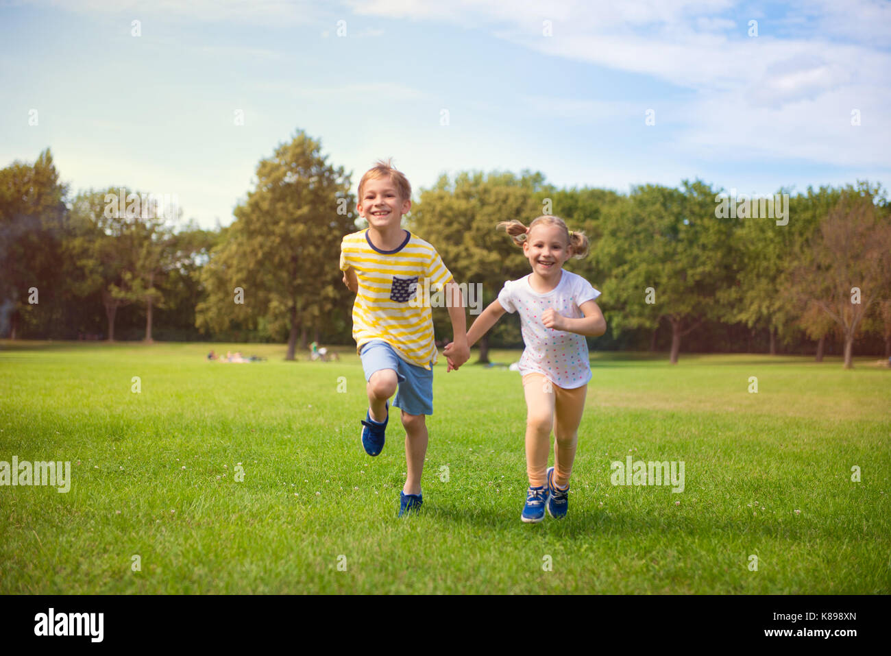 Two happy children running in summer park Stock Photo - Alamy