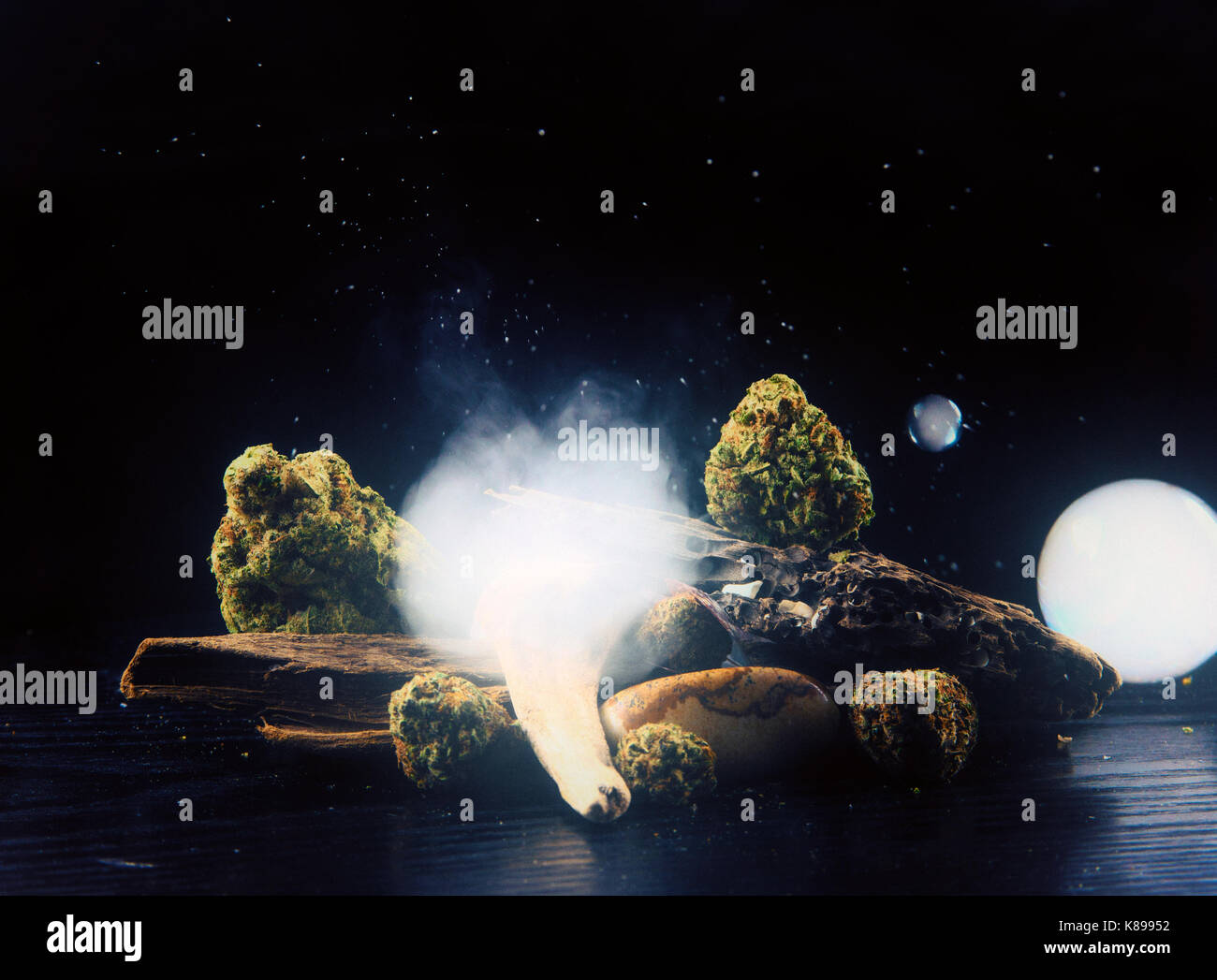 Still life with cannabis nugs, drift wood and smoke bubbles over dark ...