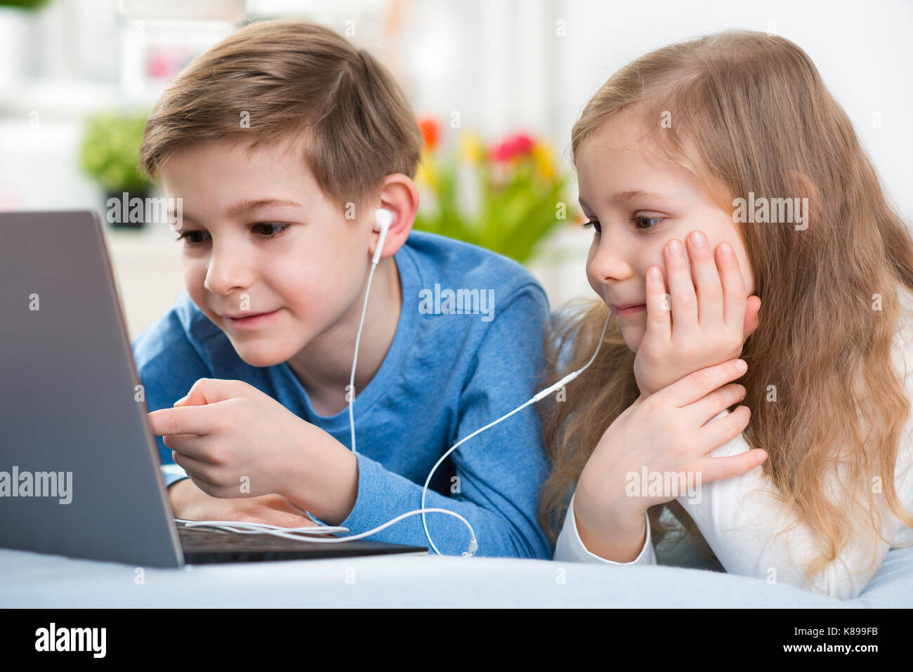 Two happy children playing with laptop and listening music with ...