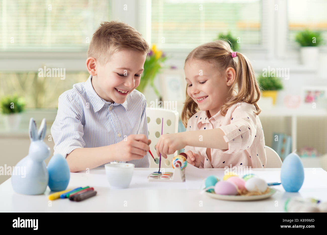 Two happy children having fun during painting eggs for easter in spring ...