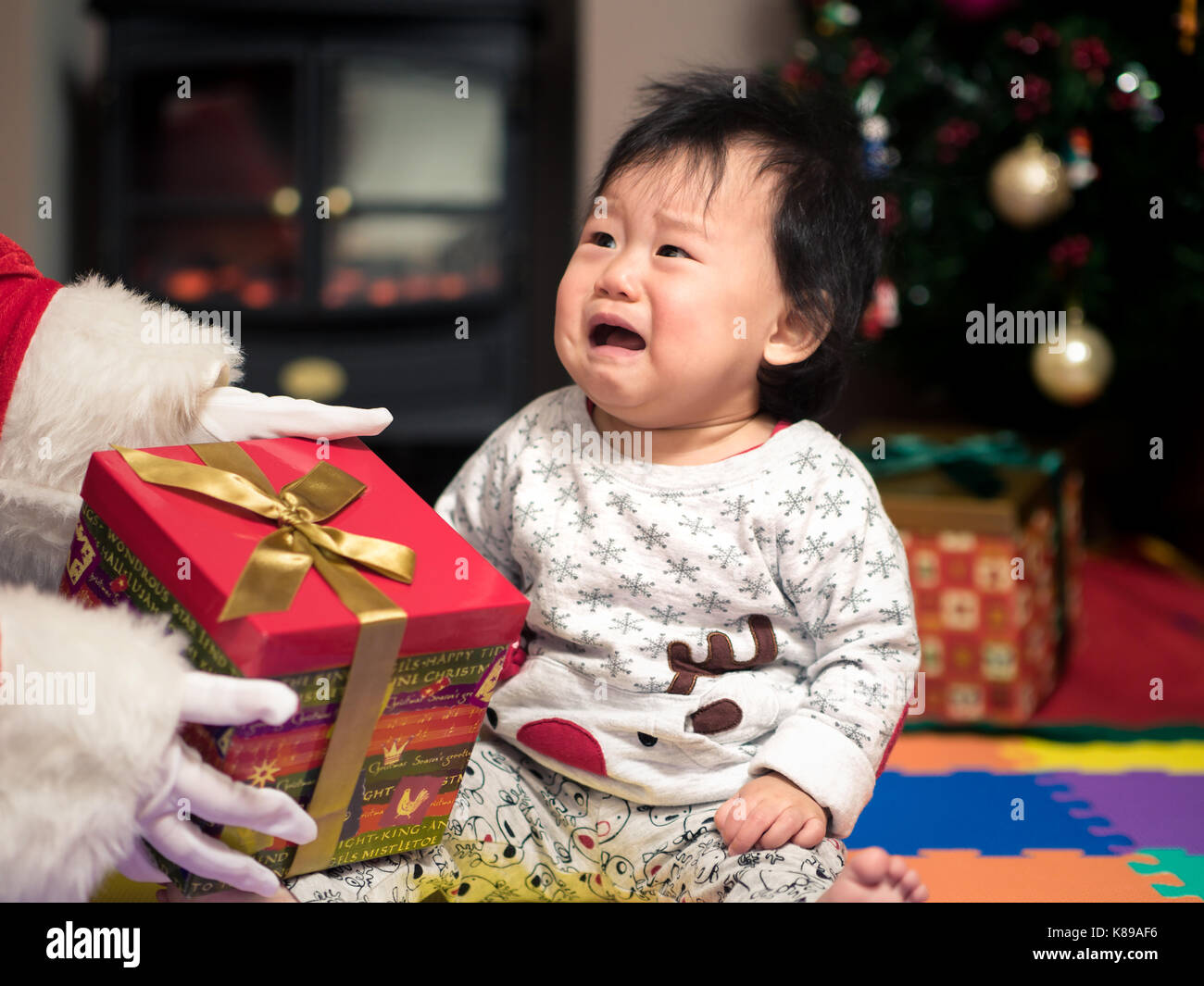 Santa claus bring a gift box to crying baby girl Stock Photo - Alamy
