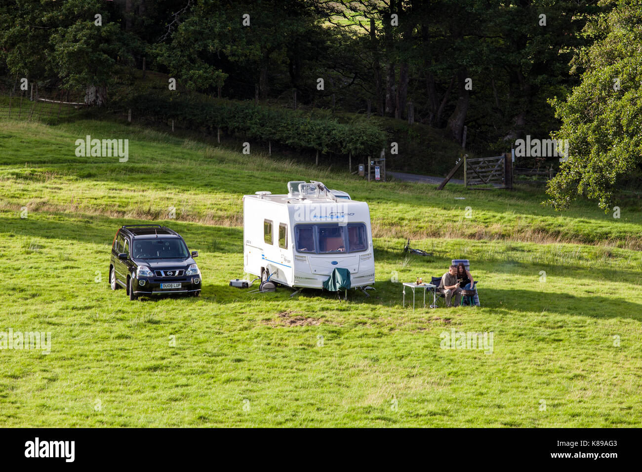 Man and woman enjoying a barbecue outdoors outside their touring ...