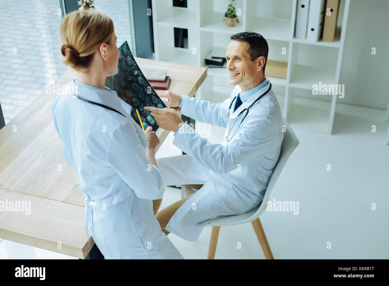 Delighted smart doctor smiling to his colleague Stock Photo - Alamy