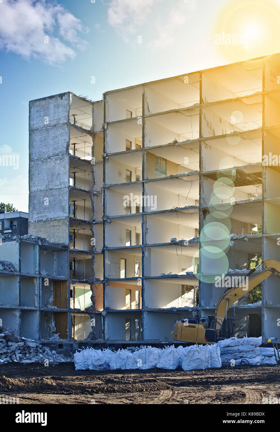 Demolished residential building with excavator and huge plastic bags ...
