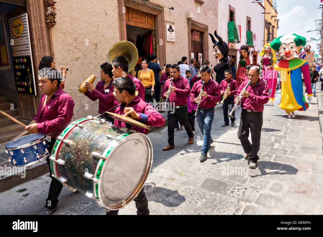 A brass band leads a procession of giant papier mache puppets called ...