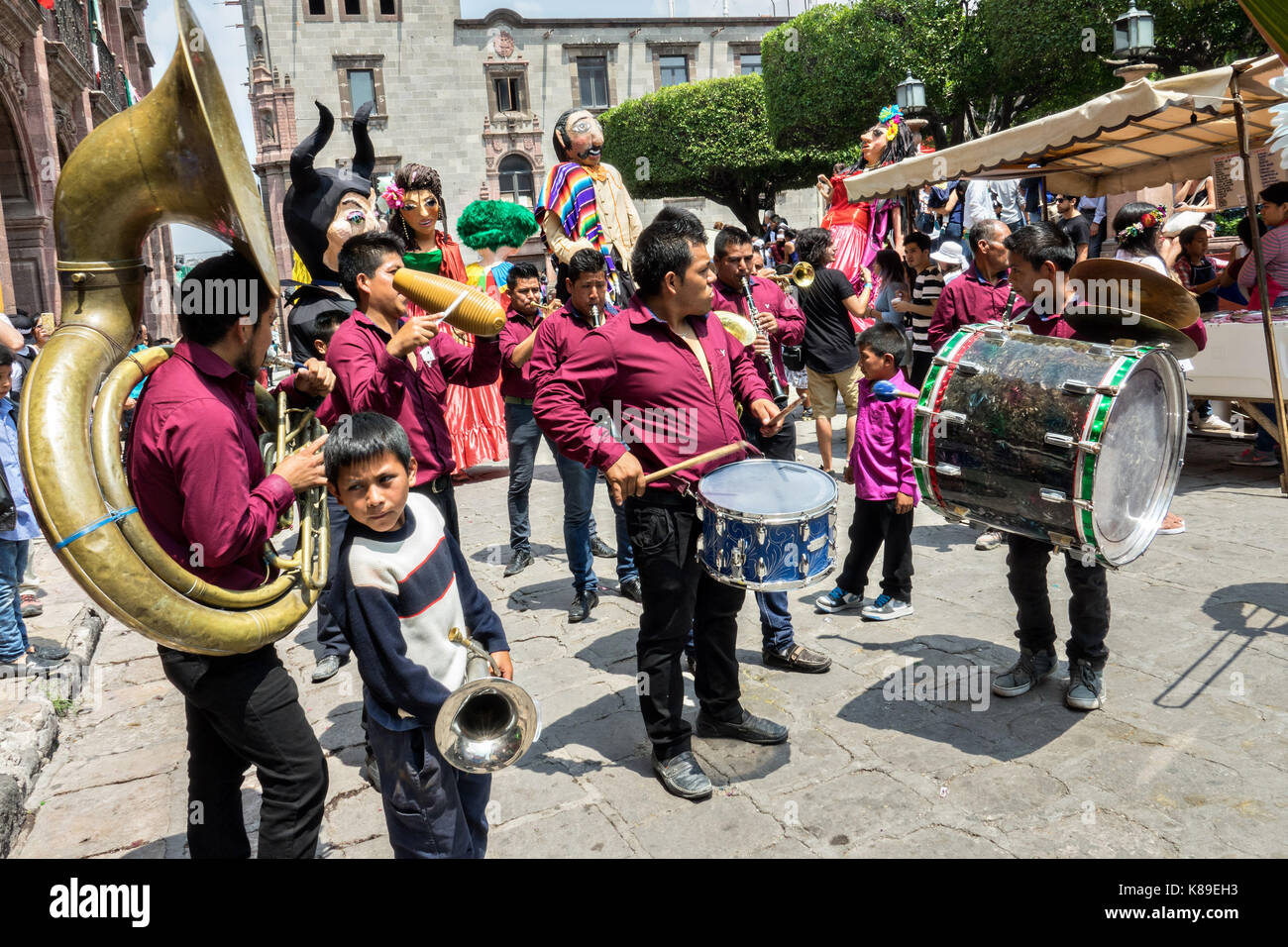 A brass band leads a procession of giant papier mache puppets called ...