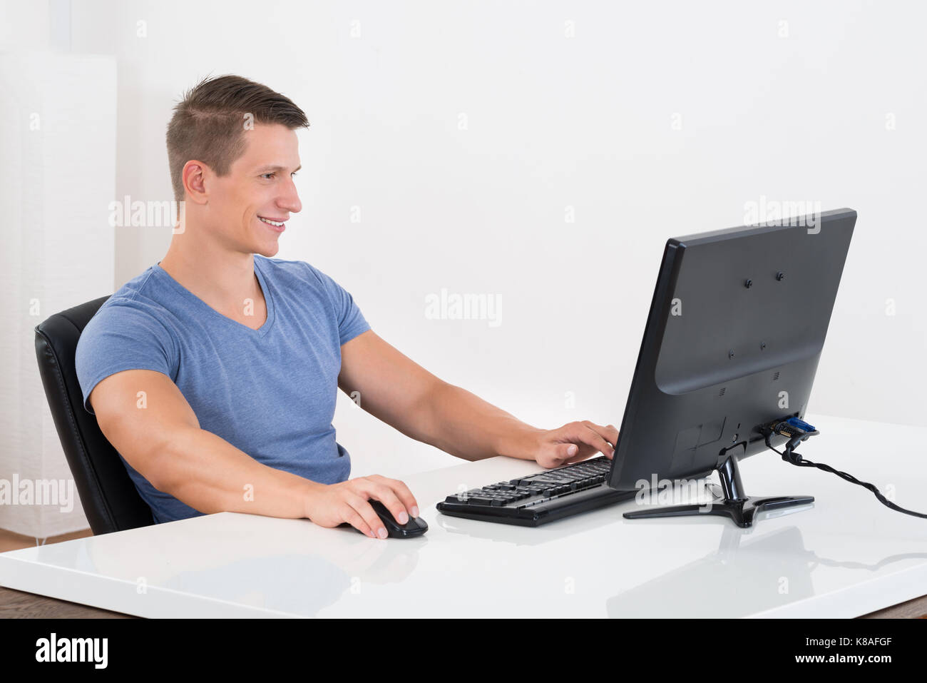 Young Man Working On Desktop Computer At Desk Stock Photo - Alamy