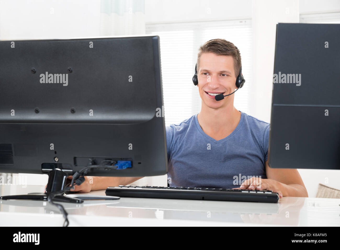 Happy Man Talking With Headset On Computer At Desk Stock Photo - Alamy