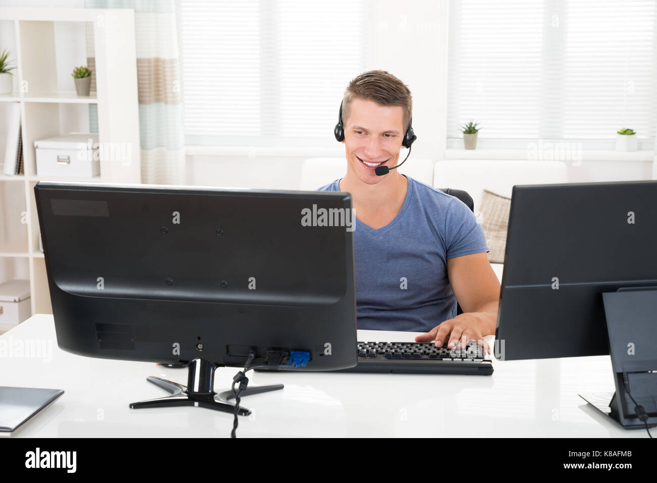 Happy Man Talking With Headset On Computer At Desk Stock Photo - Alamy