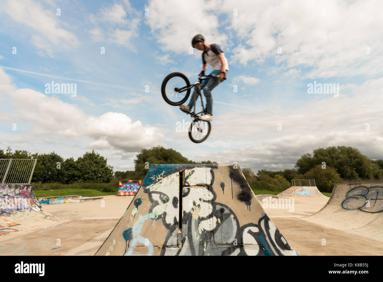 Young male box rider switches over the spine of a concrete half pipe ...