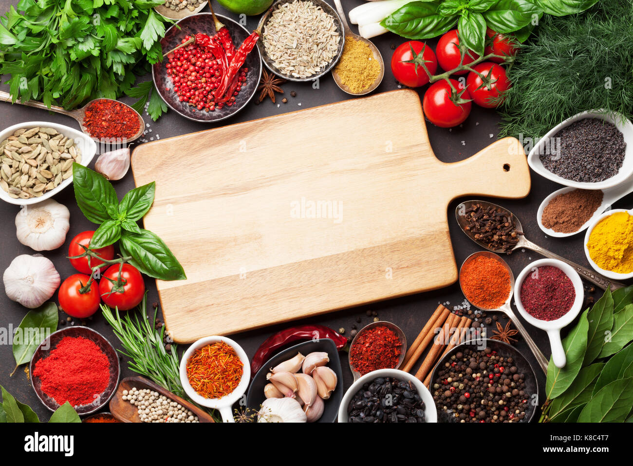 Various spices, herbs and cutting board on stone table. Top view with ...