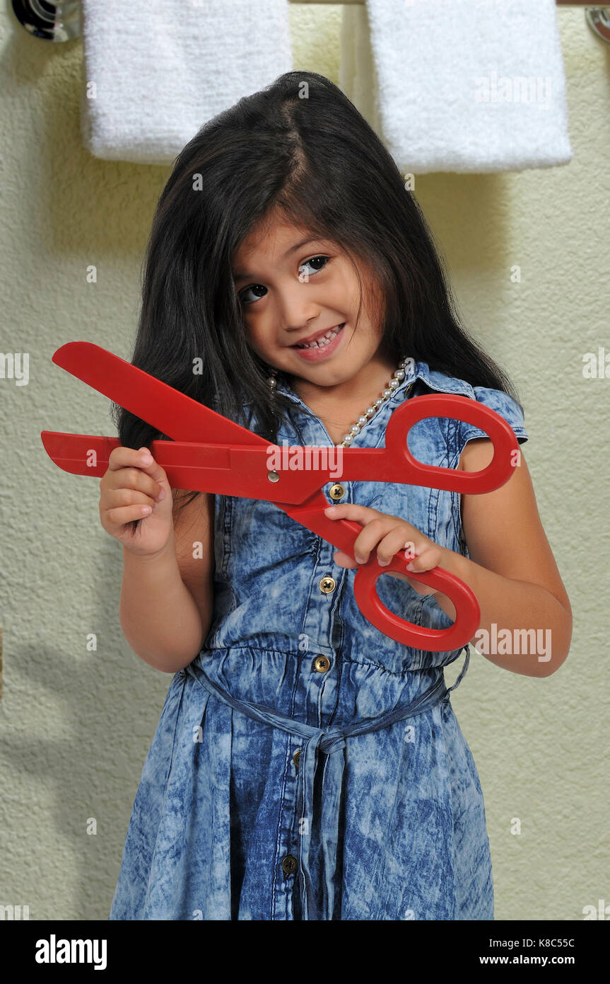 Little girl with big scissors cutting her hair Stock Photo - Alamy
