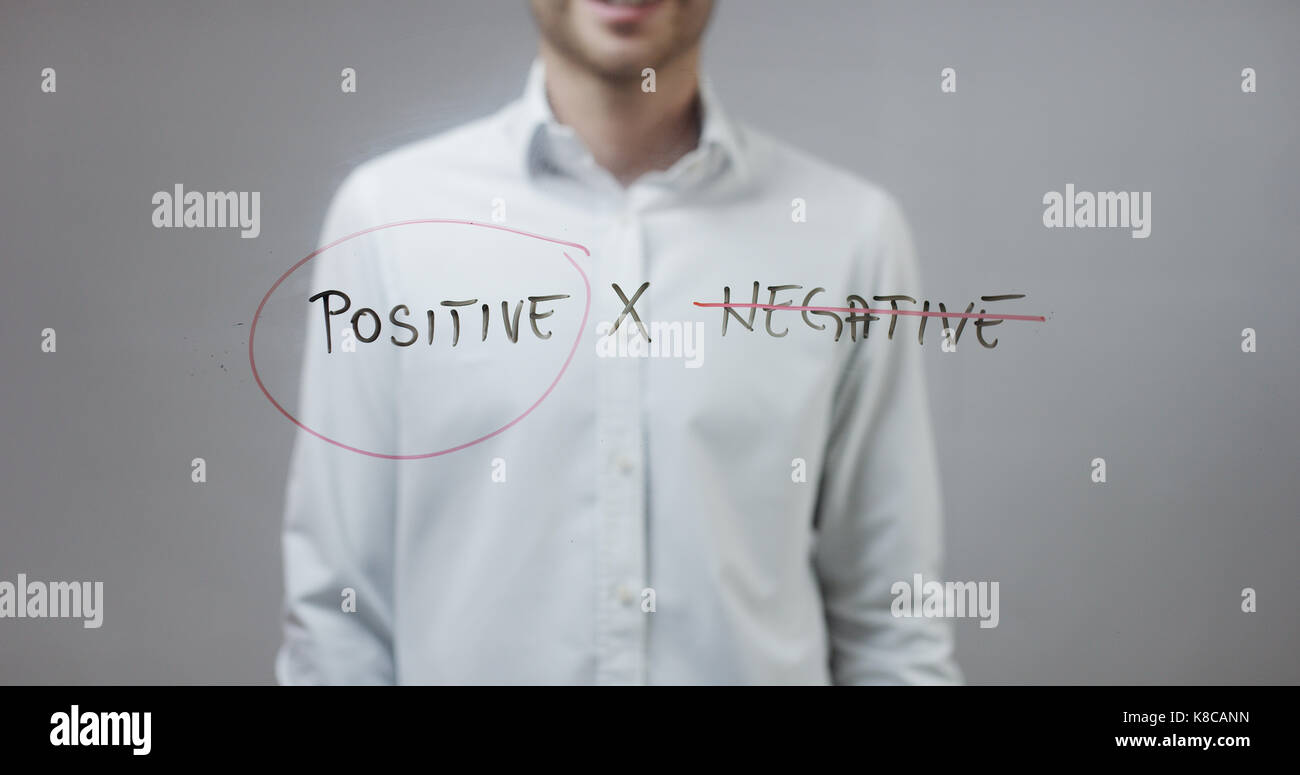 Positive vs negative , Man Writing on Glass Stock Photo - Alamy