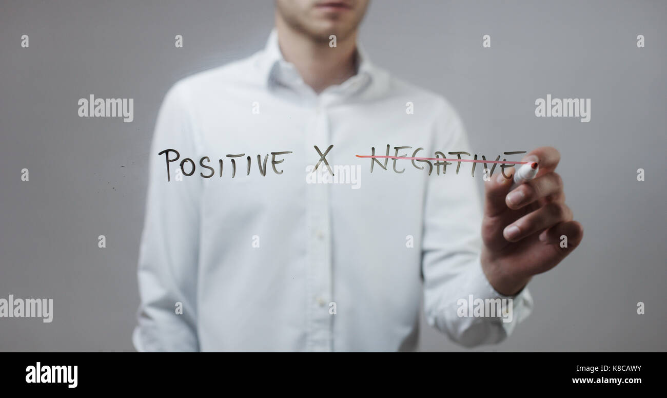 Positive vs negative , Man Writing on Glass Stock Photo - Alamy