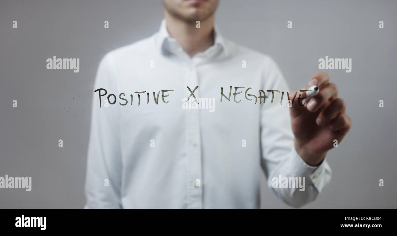 Positive vs negative , Man Writing on Glass Stock Photo - Alamy