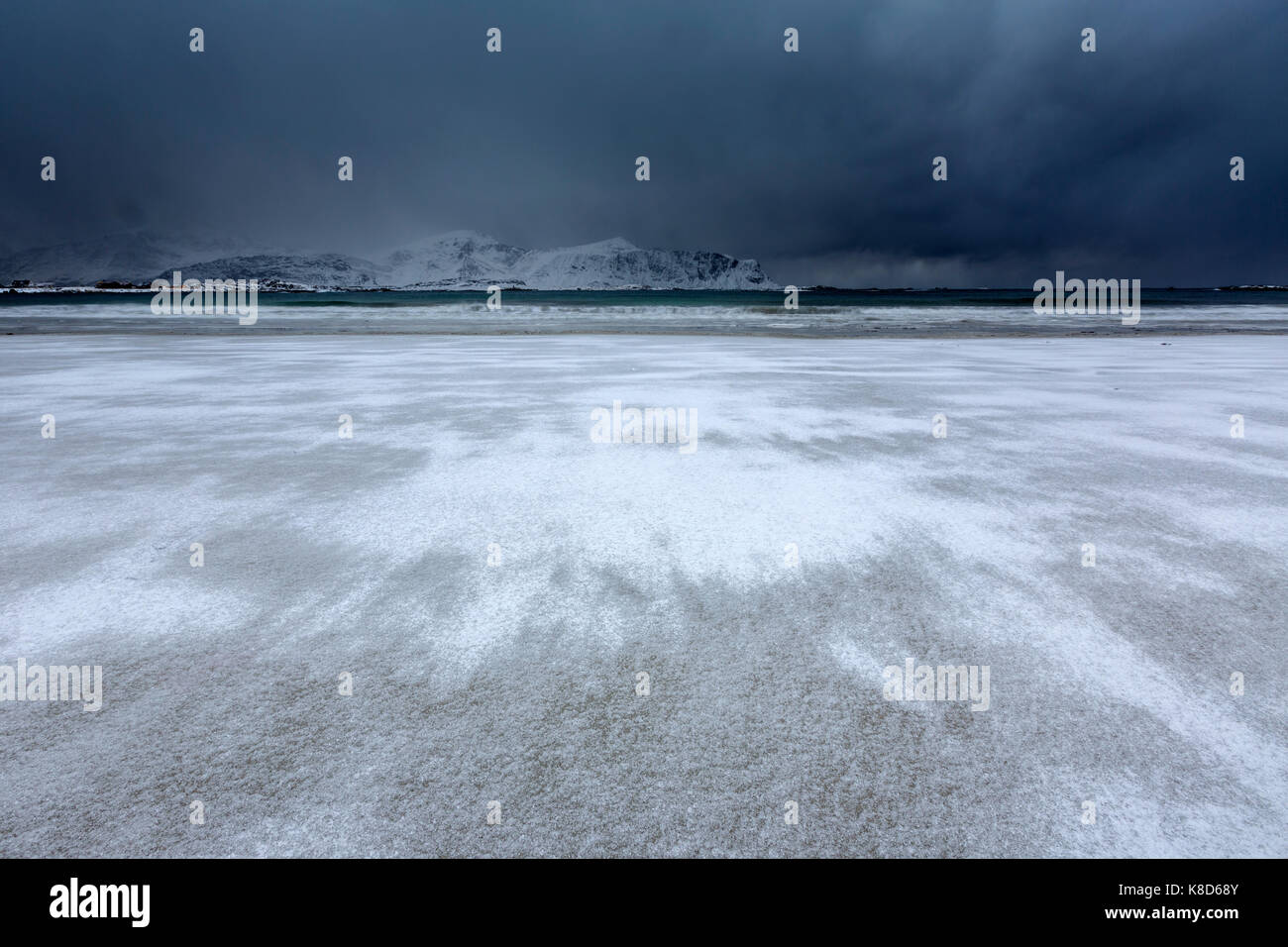 Waves of the icy sea on the beach in the background the snowy peaks ...