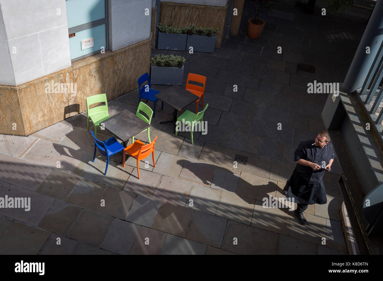 A chef takes a cigarette break near colourful seating in the City of ...