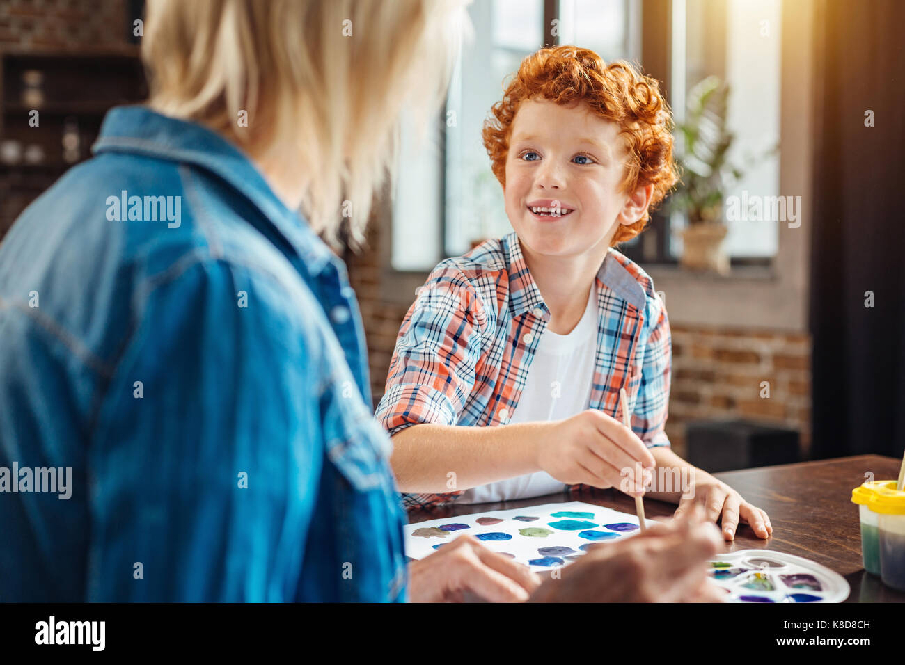 Cute ginger boy smiling broadly while looking at grandmother Stock ...