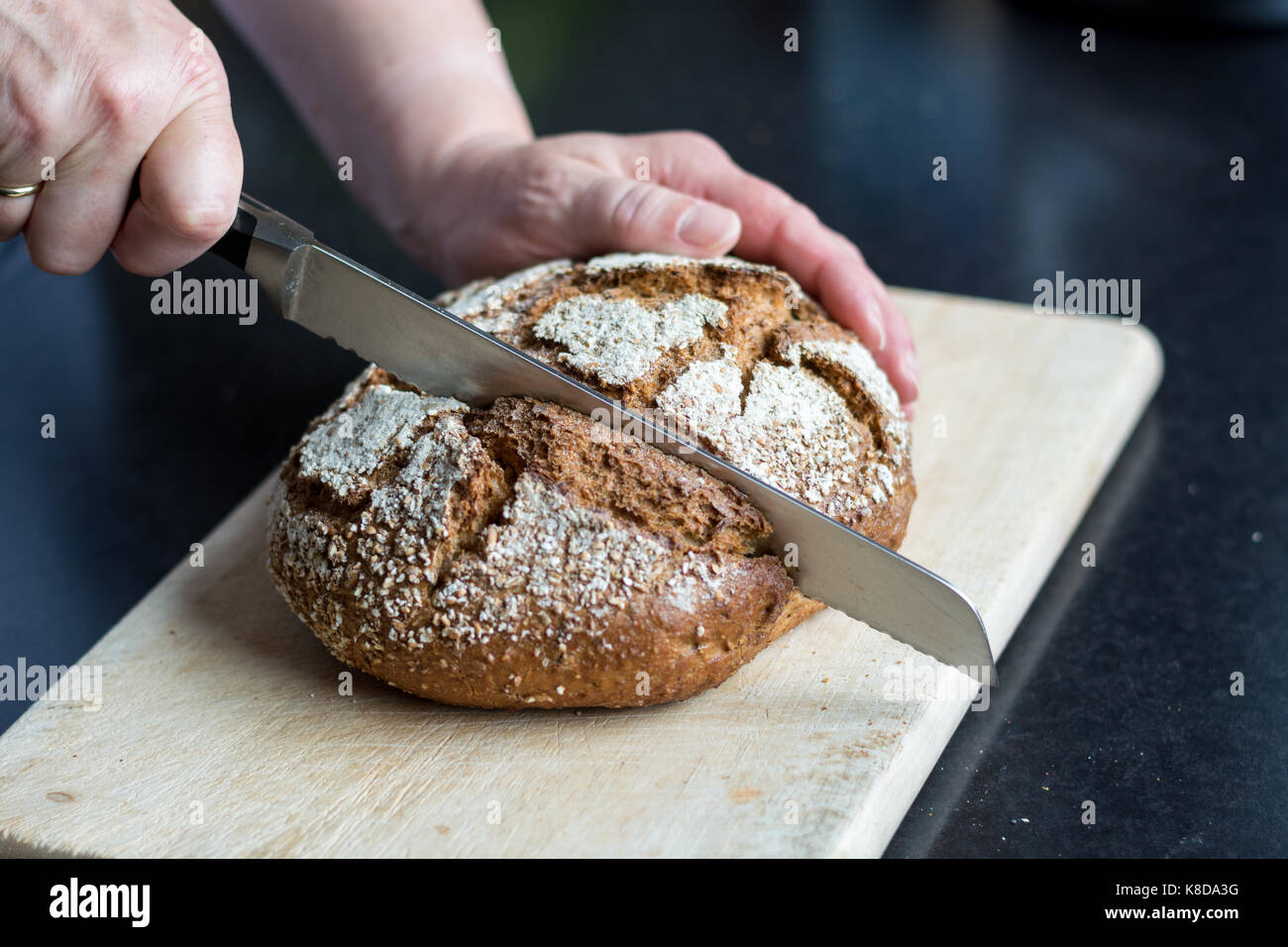 Cutting loaf of bread with knife on cutting board close up Stock Photo ...