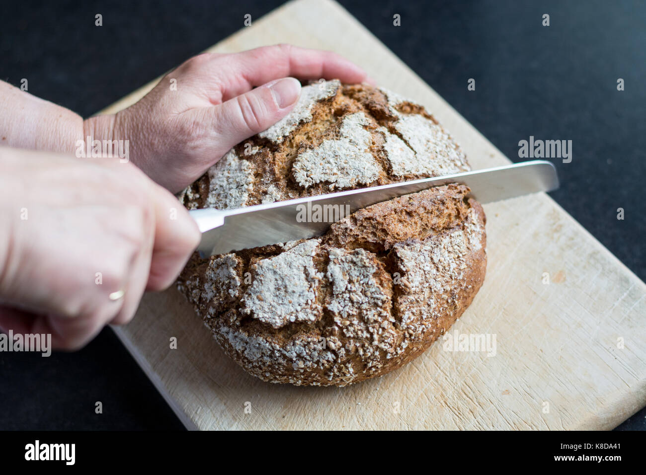 Cutting loaf of bread with knife on cutting board close up Stock Photo ...