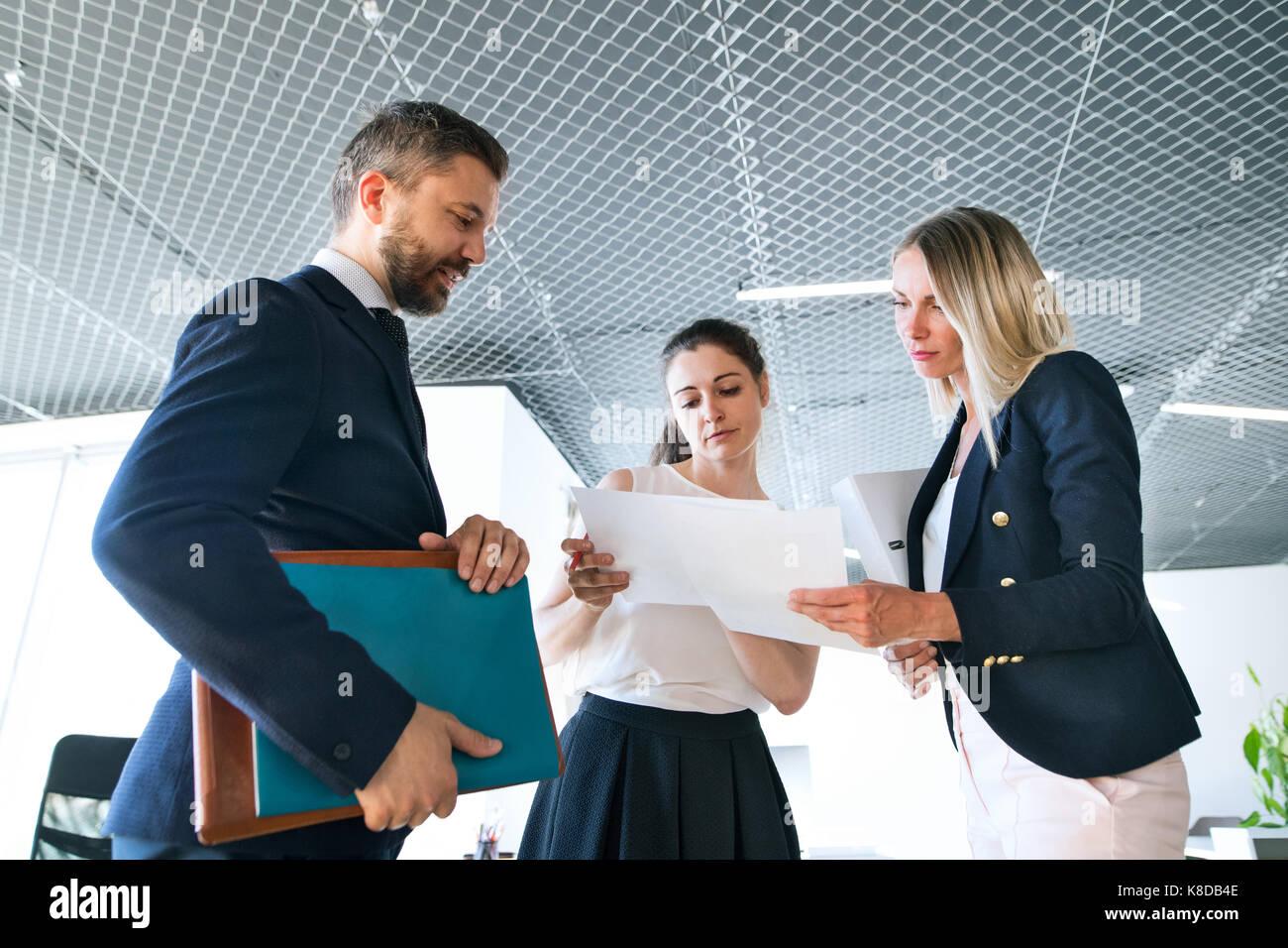 Three business people in the office talking together Stock Photo - Alamy