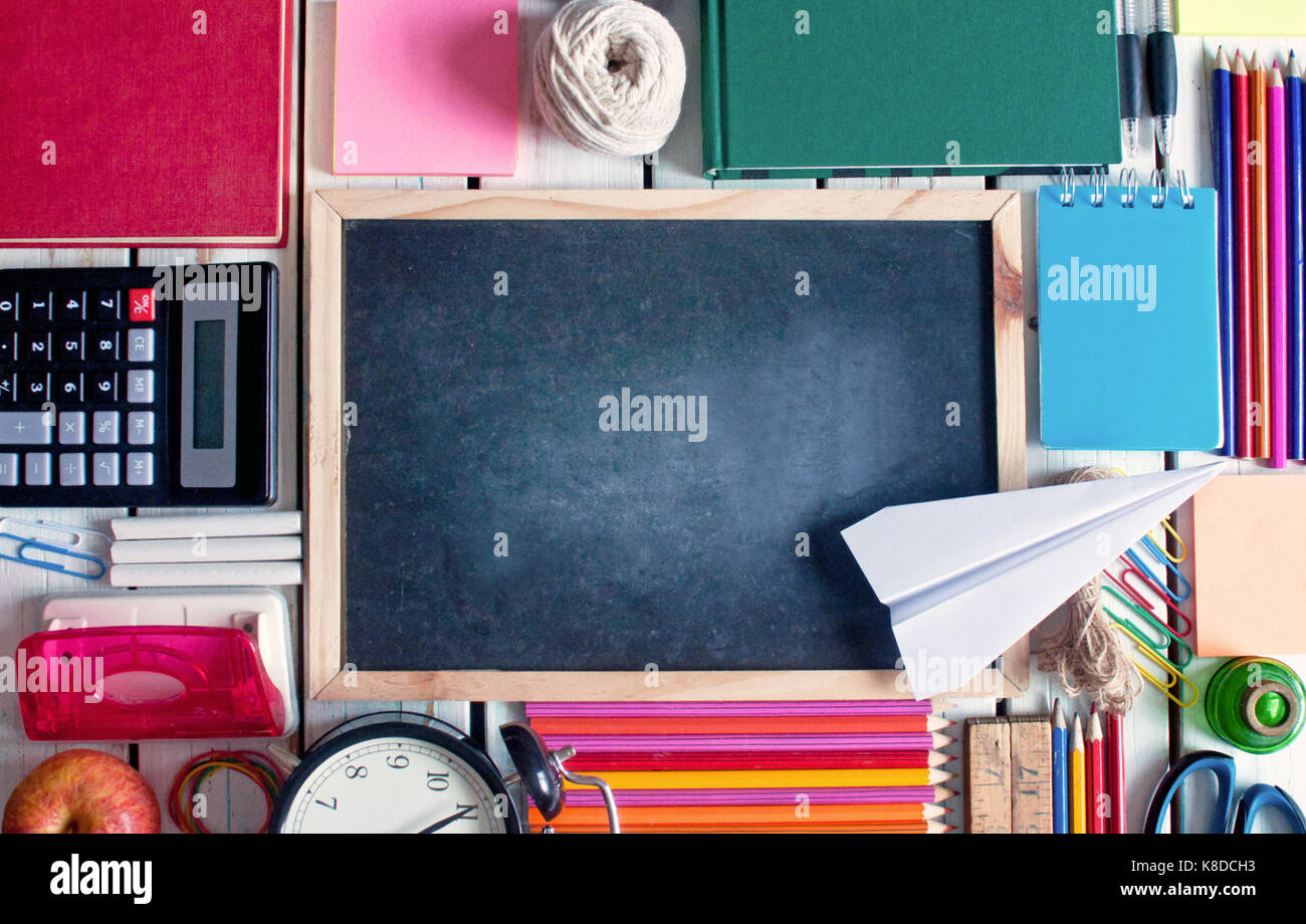 Top view of various stationery objects with blackboard in the centre ...