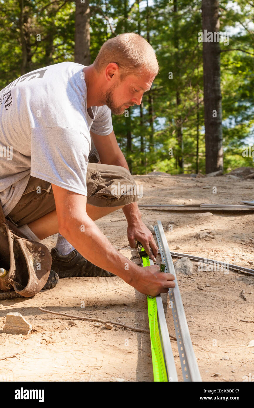 A construction worker marking vinyl edging using a pencil and a tape ...