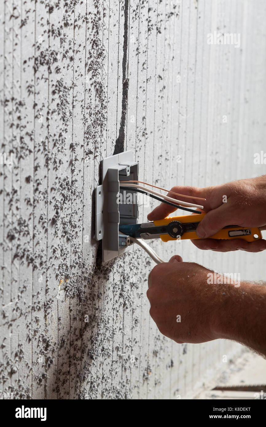 An electrician installing an electrical utility box into insulated ...