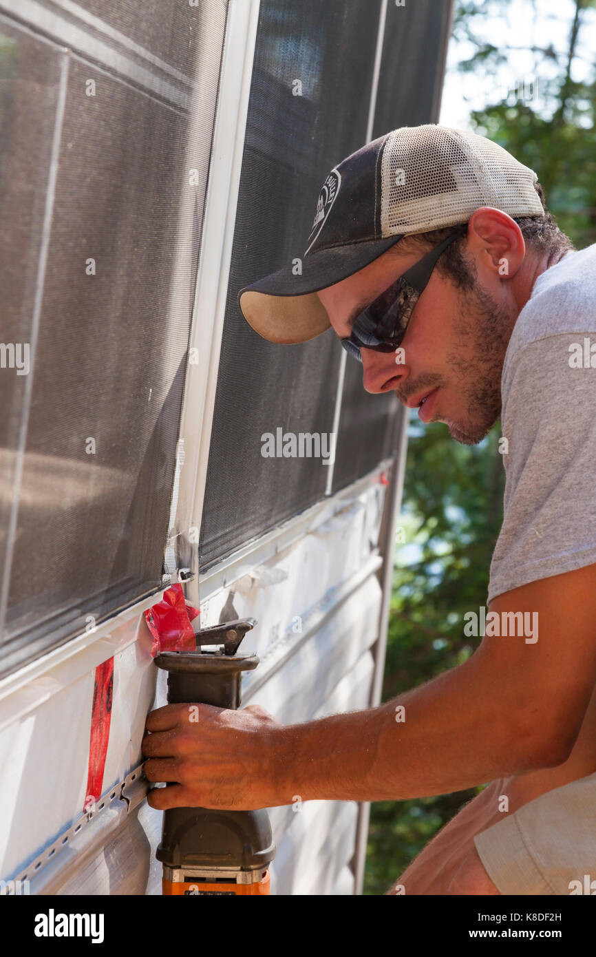 A construction working cutting a window frame using a reciprocating saw ...