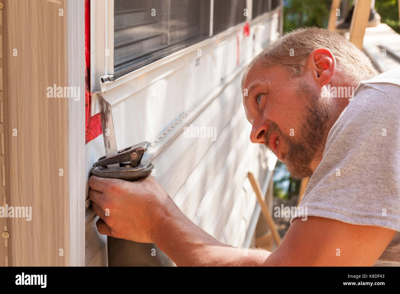 A construction working cutting a window frame using a reciprocating saw ...
