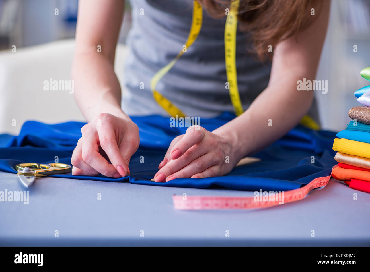 Woman tailor working on a clothing sewing stitching measuring fabric ...
