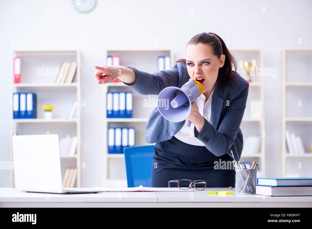 Angry businesswoman yelling with loudspeaker in office Stock Photo - Alamy
