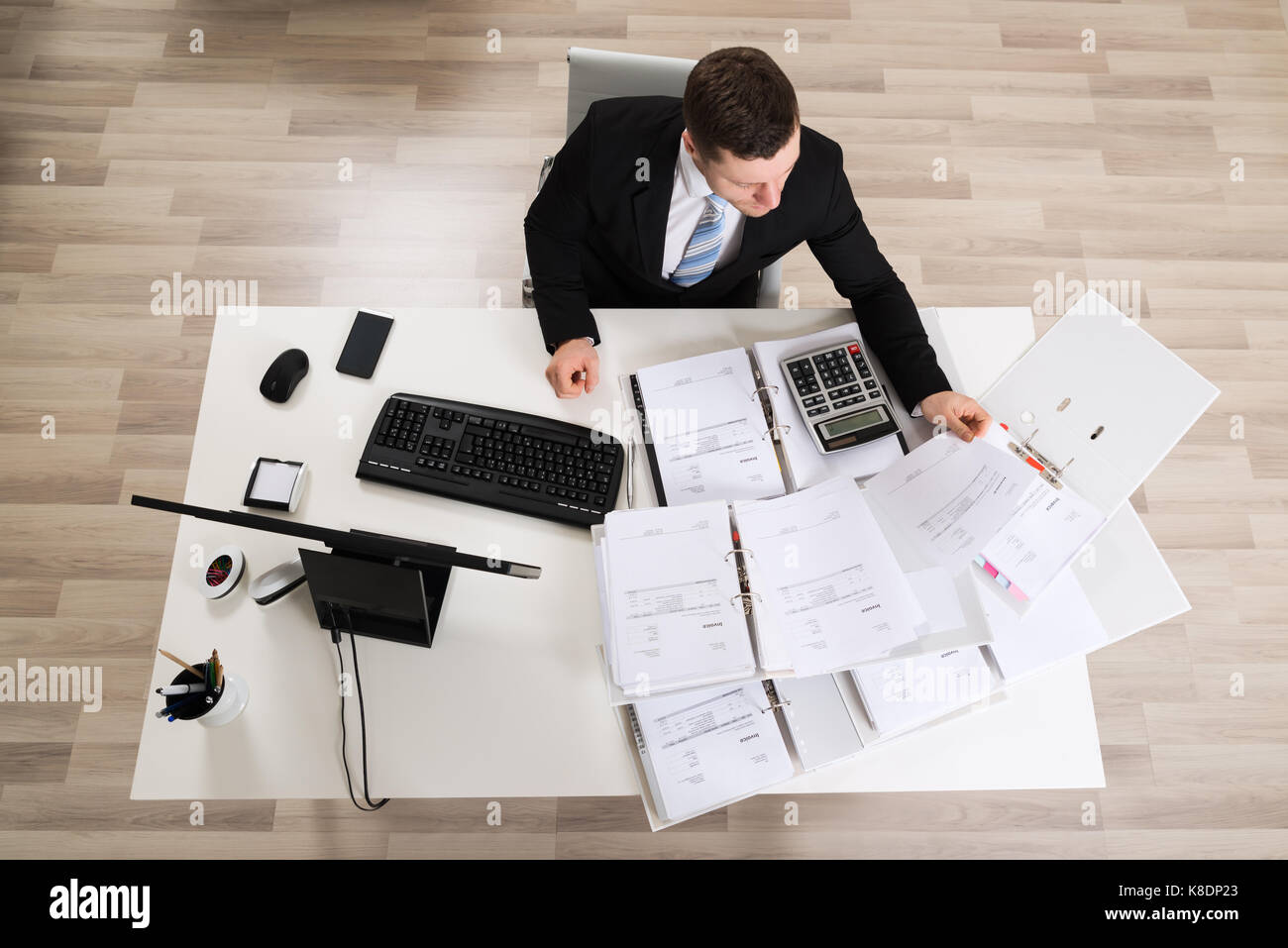 High angle view of businessman analyzing documents at computer desk in ...