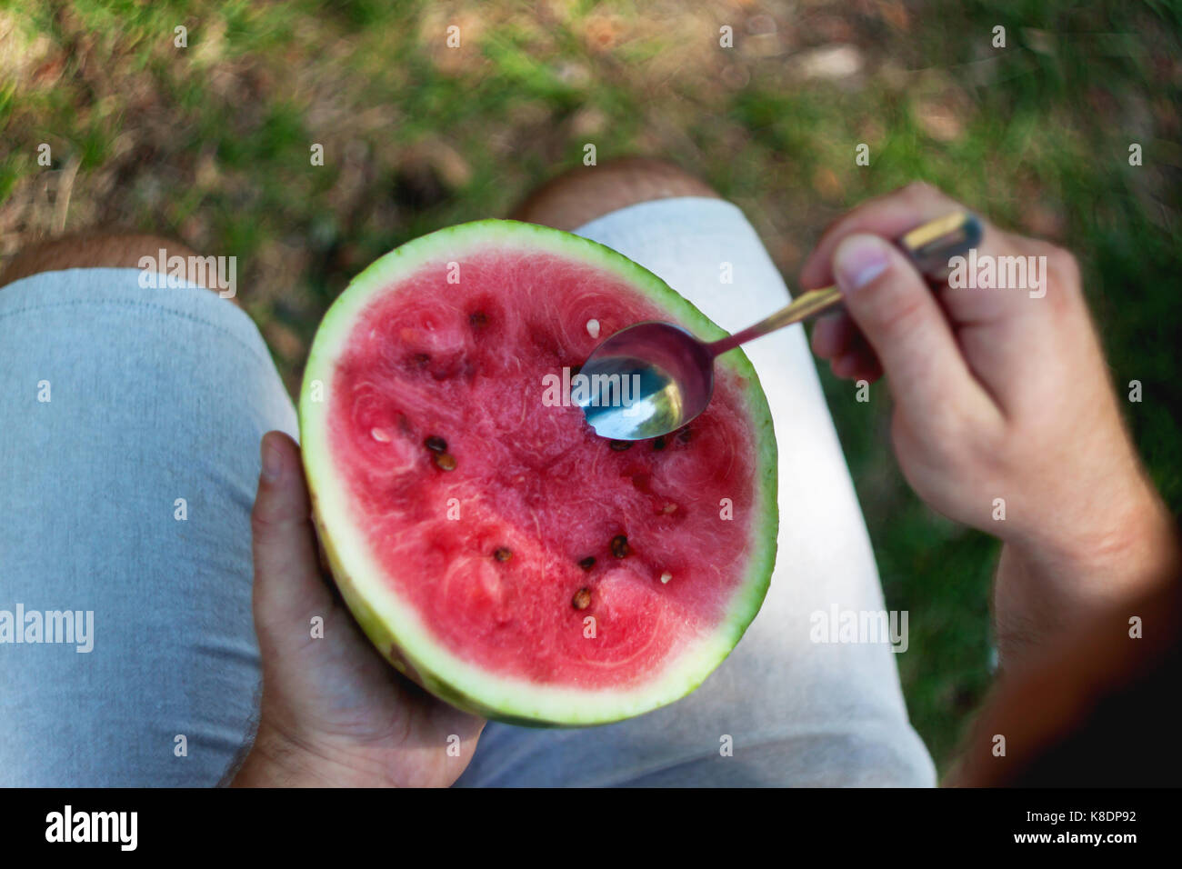 A young man is eating a watermelon with a spoon. The concept of healthy ...