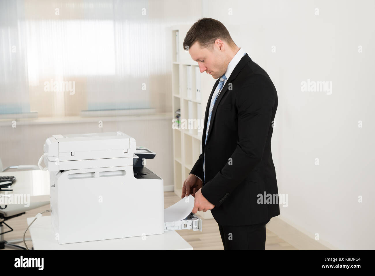 Side view of businessman inserting paper in photocopy machine at office ...