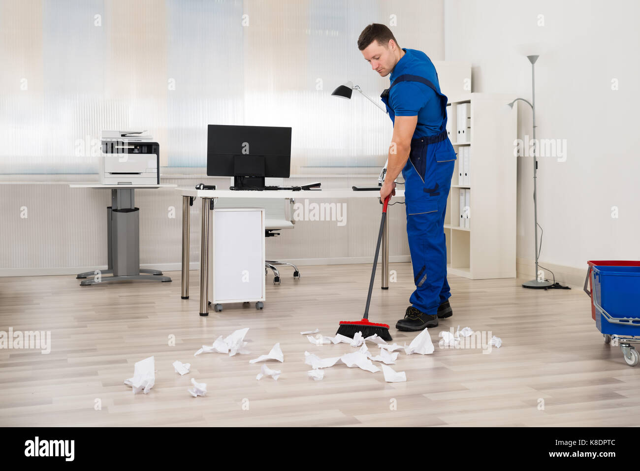 Full length of male janitor cleaning floor with broom in office Stock ...