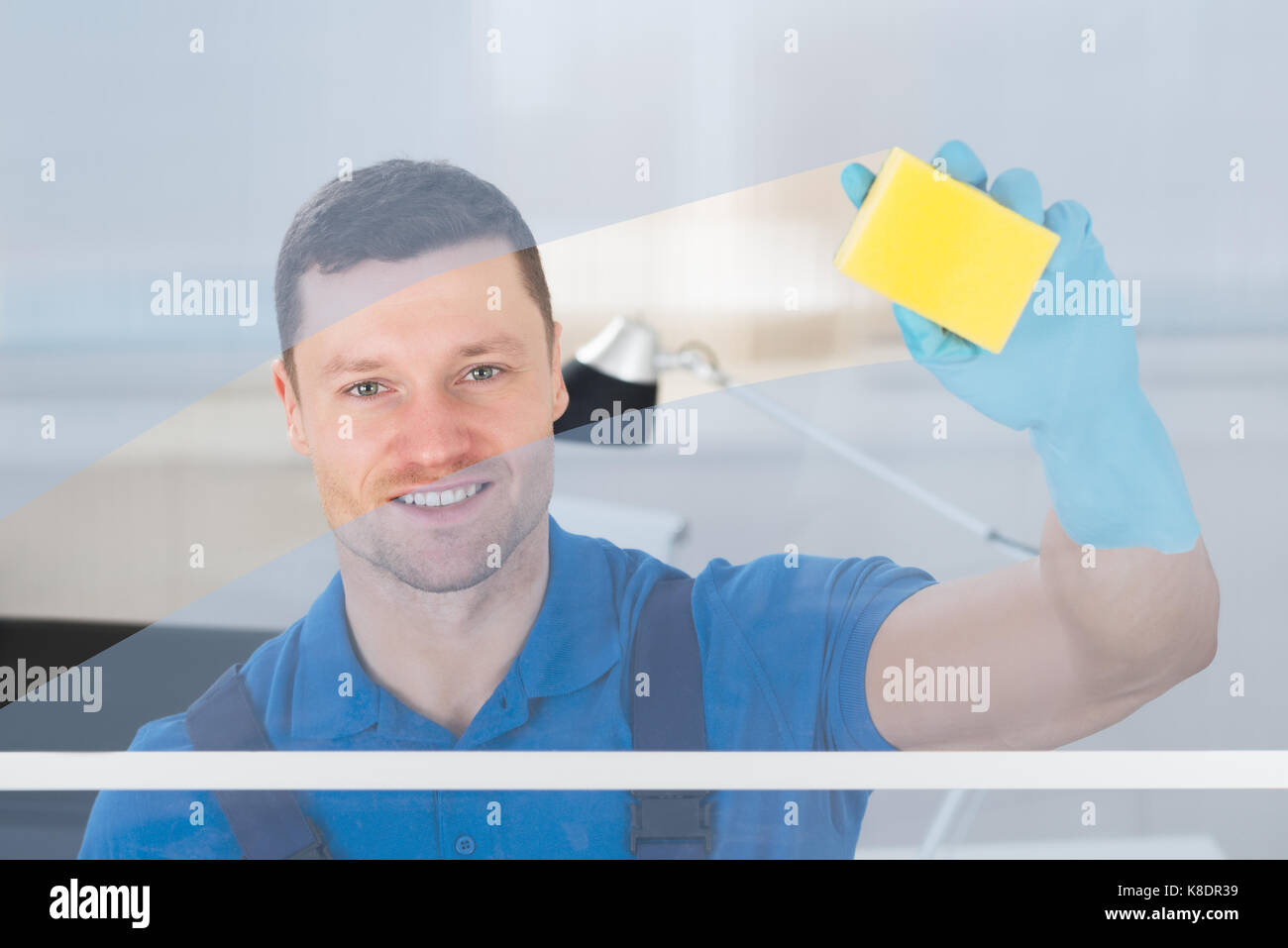 Mid adult male worker cleaning glass window with rag Stock Photo - Alamy
