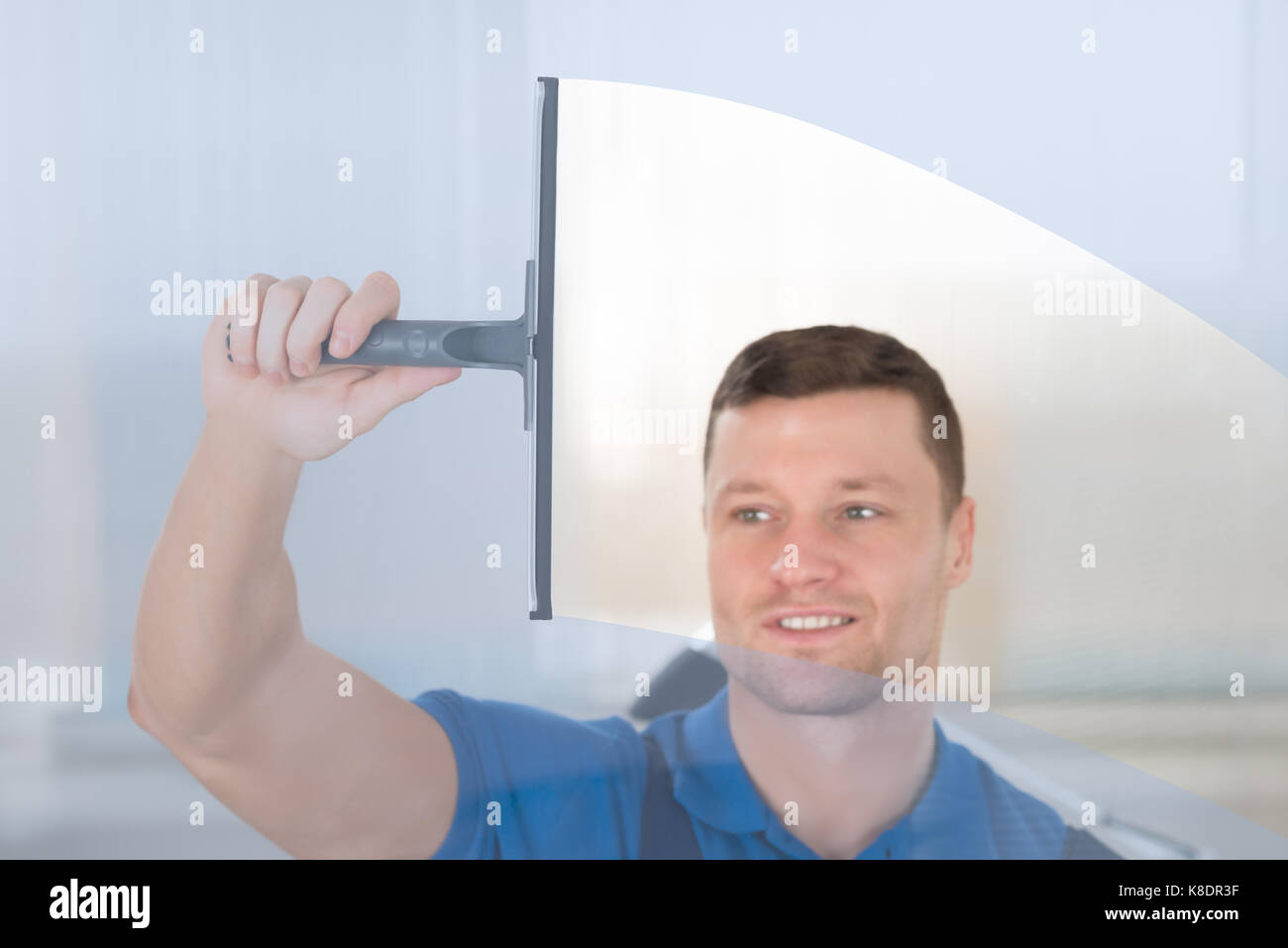 Smiling mid adult worker cleaning glass window with squeegee Stock ...