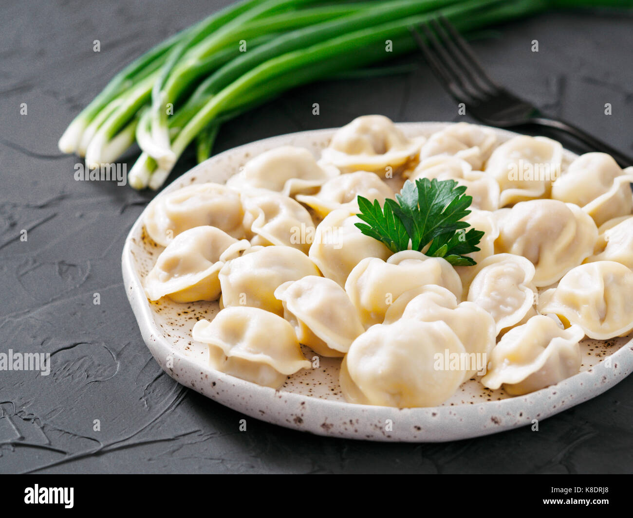 Traditional russian pelmeni, ravioli, dumplings with meat on black ...