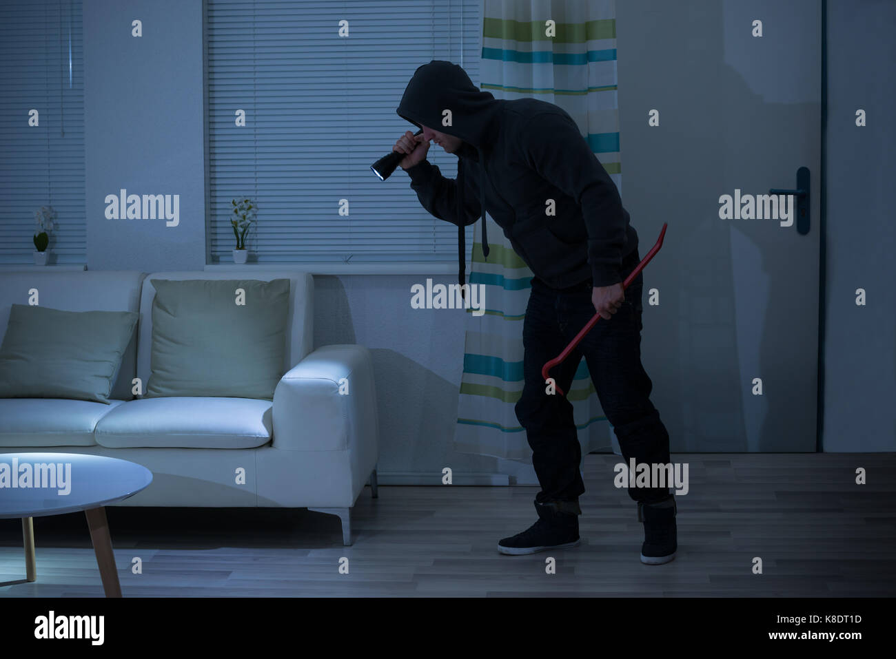 Full length of robber with crowbar and flashlight in living room Stock ...