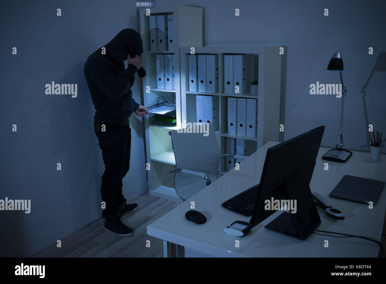 Robber with flashlight searching for documents in office at night Stock ...