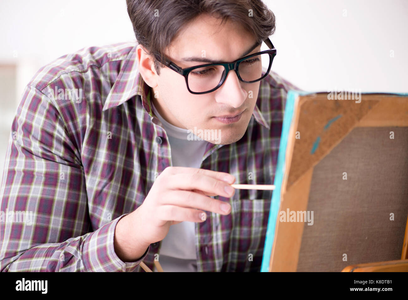 Young male artist drawing pictures in bright studio Stock Photo - Alamy