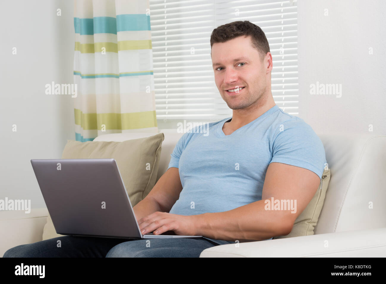 Portrait of handsome mid adult man using laptop on sofa at home Stock ...