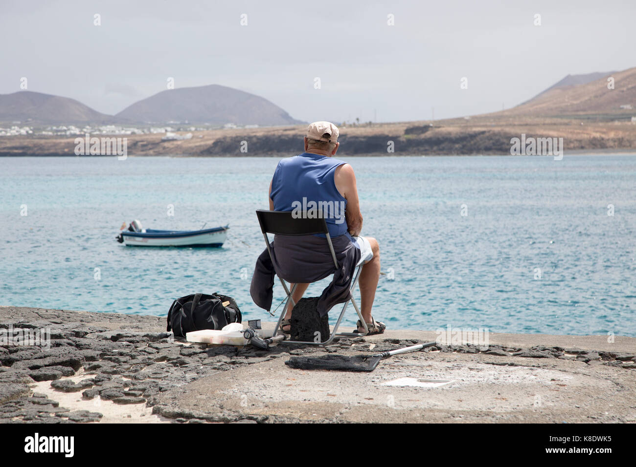 Man sitting fishing from harbour wall Arrecife, Lanzarote, Canary ...