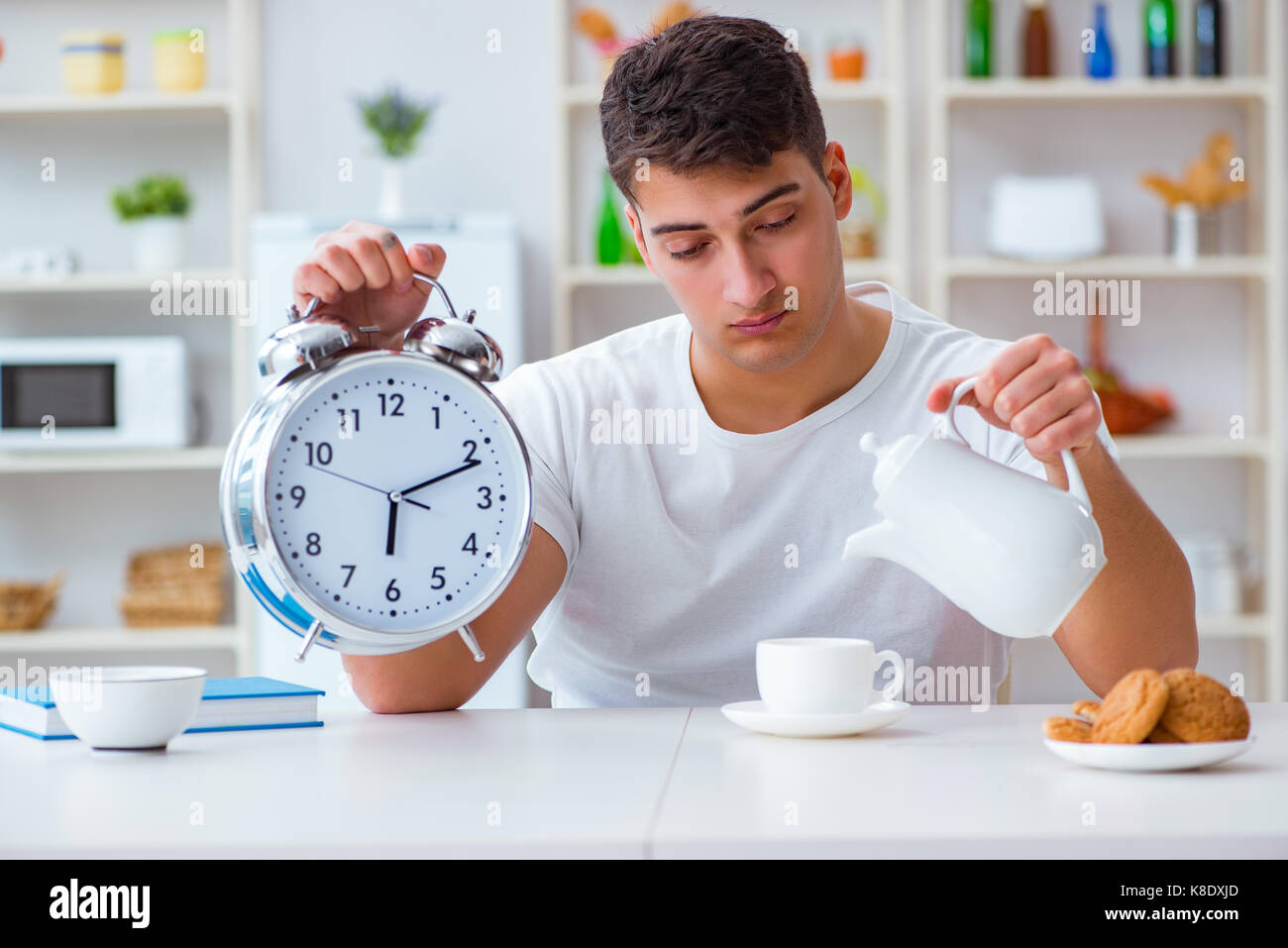 Man with alarm clock falling asleep at breakfast Stock Photo - Alamy