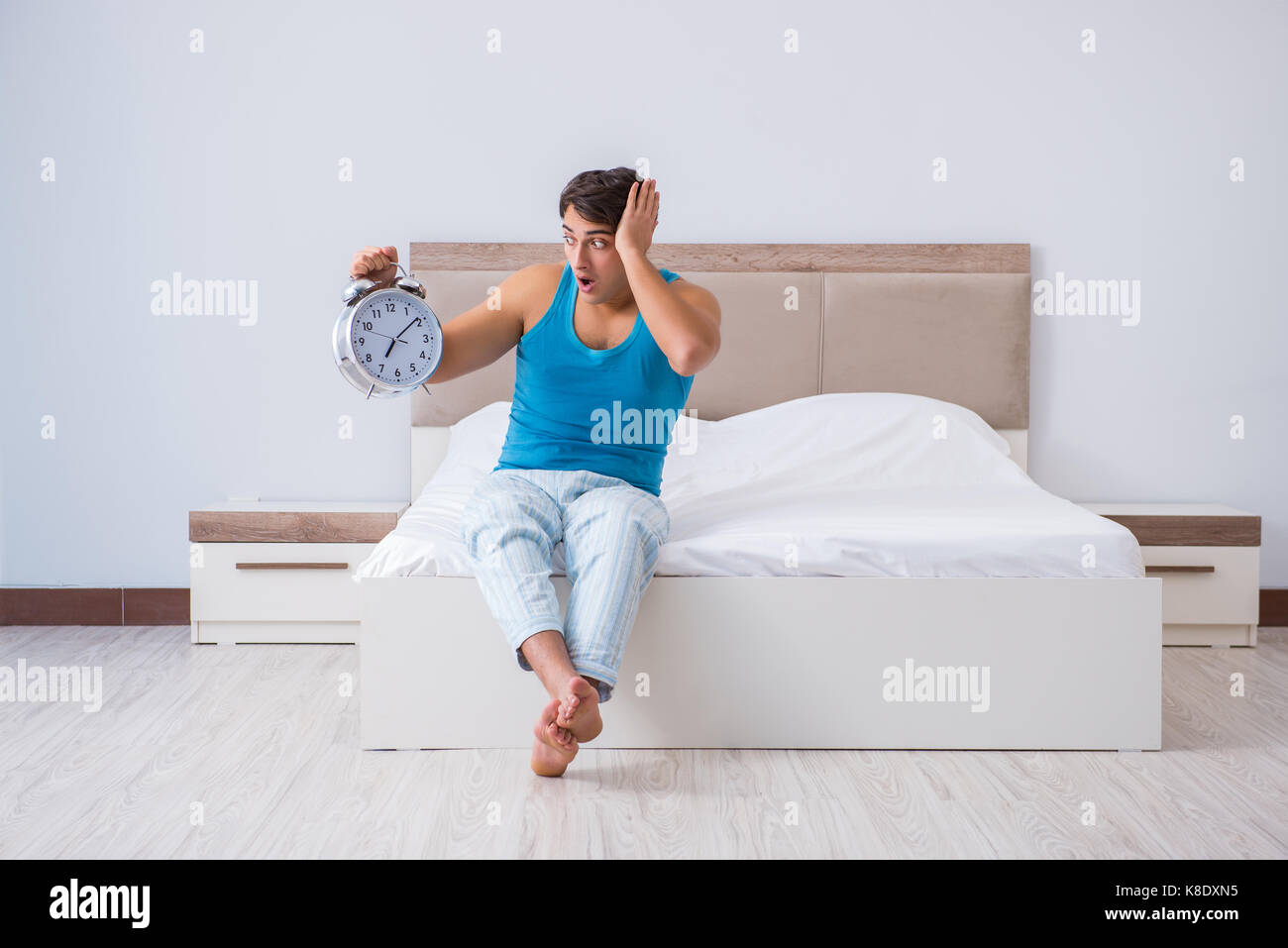 Young man waking up in bed Stock Photo - Alamy